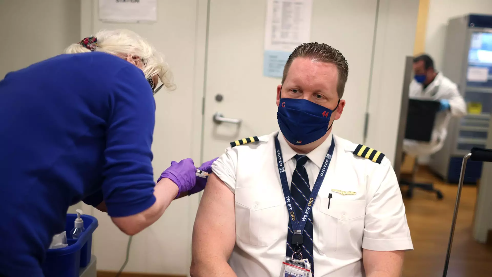 United Airlines-piloten mottar en COVID-19-vaksine fra Uniteds klinikk på O'Hare internasjonale lufthavn.