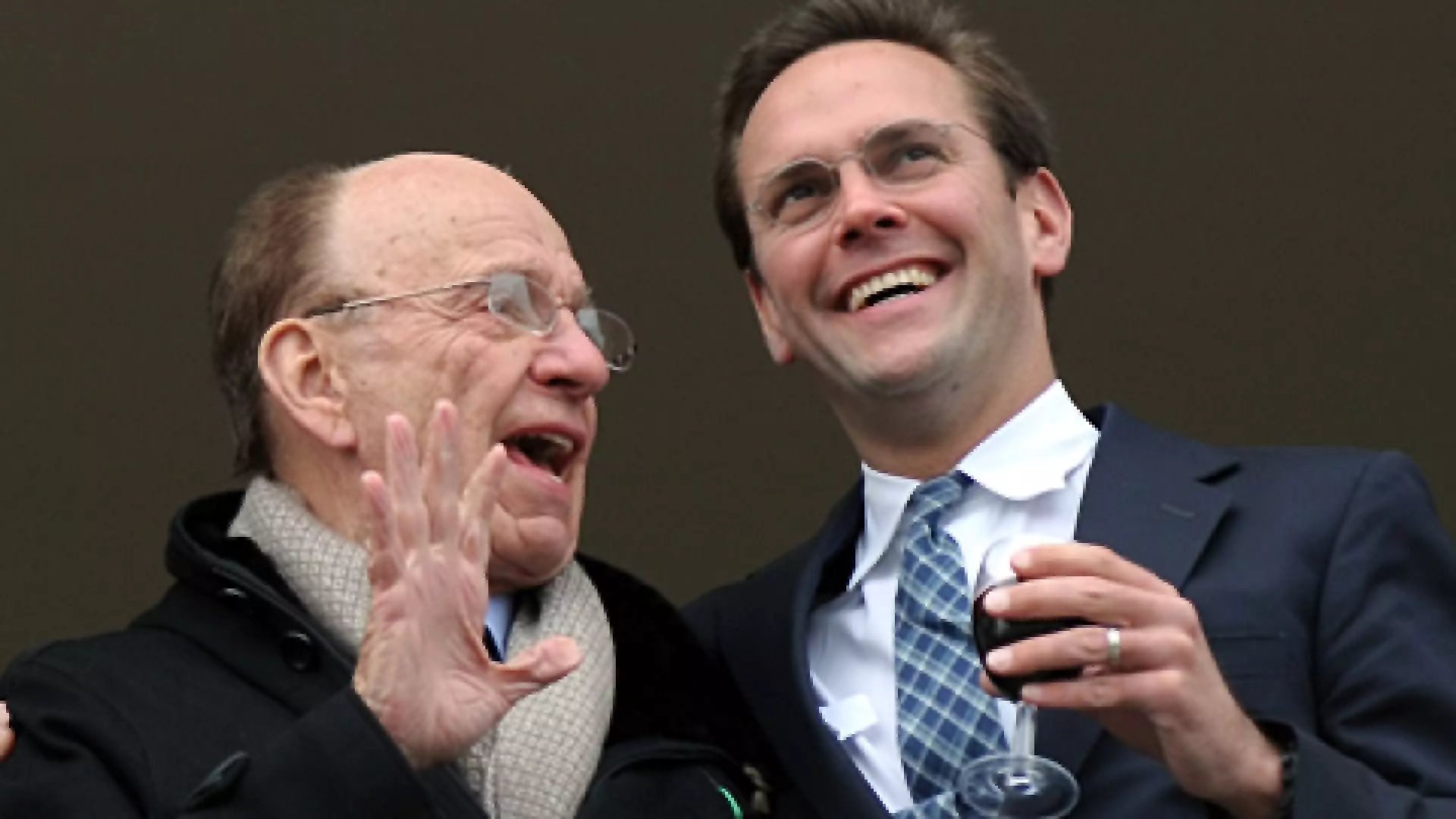 Mogulê medyayê Rupert Murdoch di Adara 2010-an de li kêleka kurê James Murdoch li balkonek ku berbi pêşbaziya hespan a Festîvala Cheltenham radiweste.